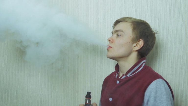 Young man vaping an electronic cigarette. Vaper hipster smoke vaporizer ...
